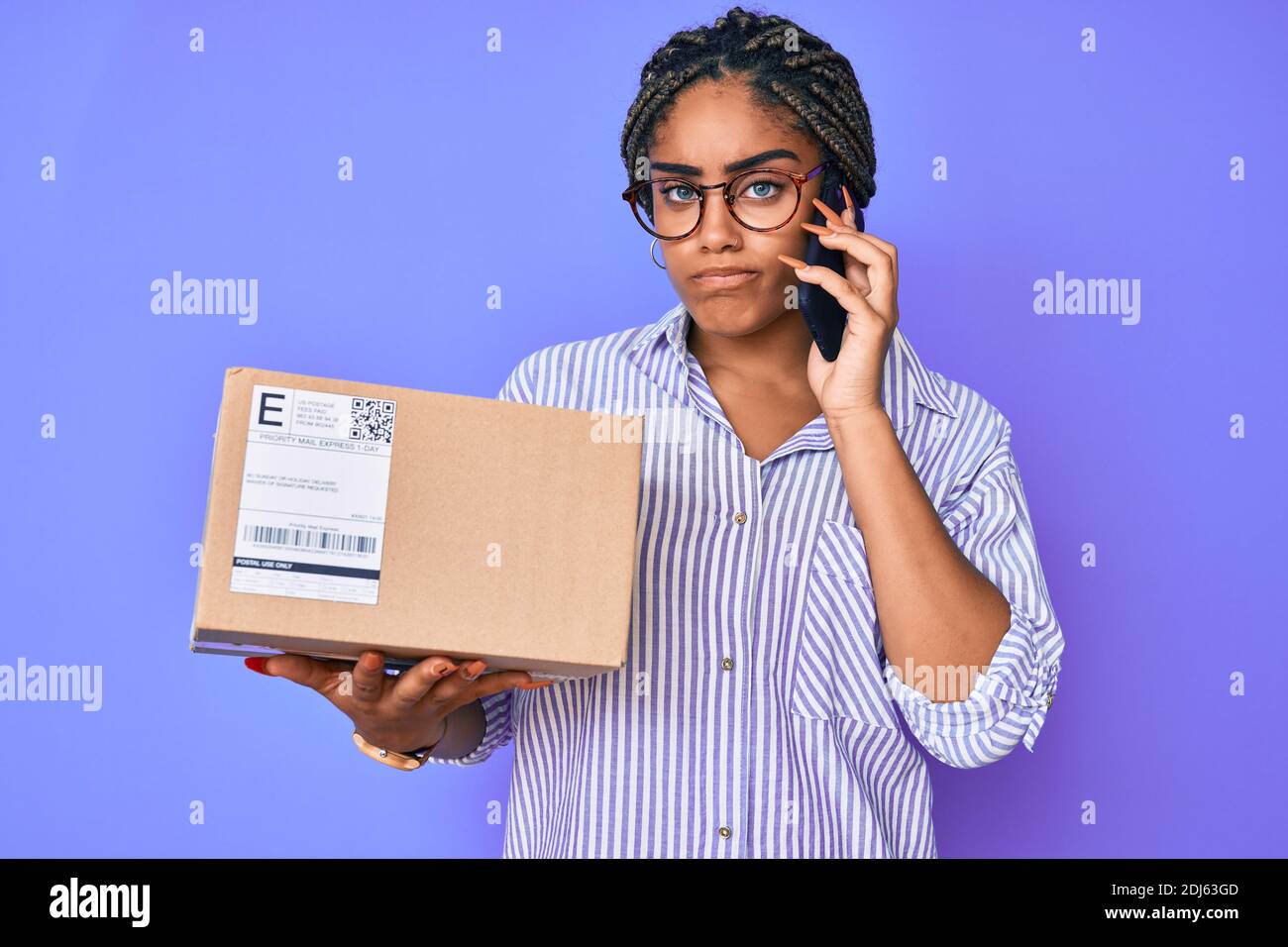 Young african american woman with braids holding delivery box calling ...
