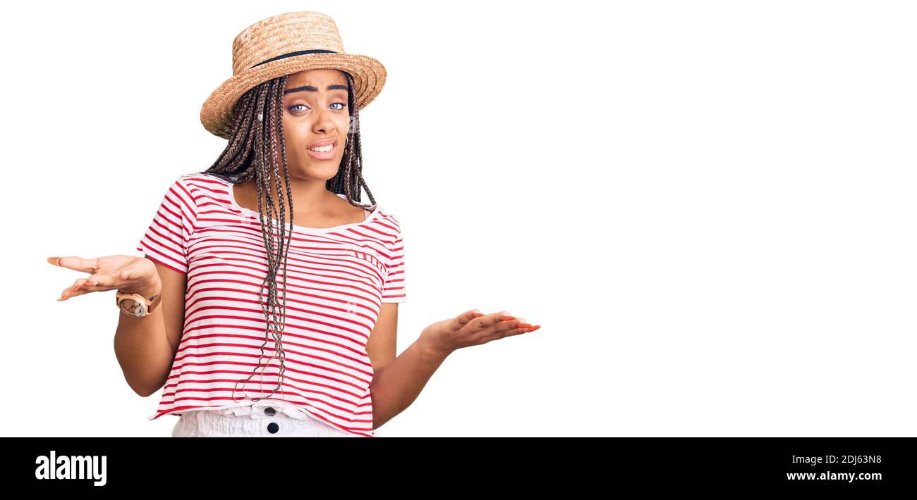 Young african american woman with braids wearing summer hat clueless ...