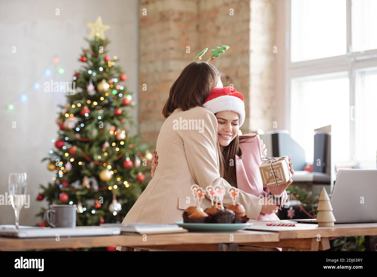 Happy young businesswoman giving hug to her female colleague while ...