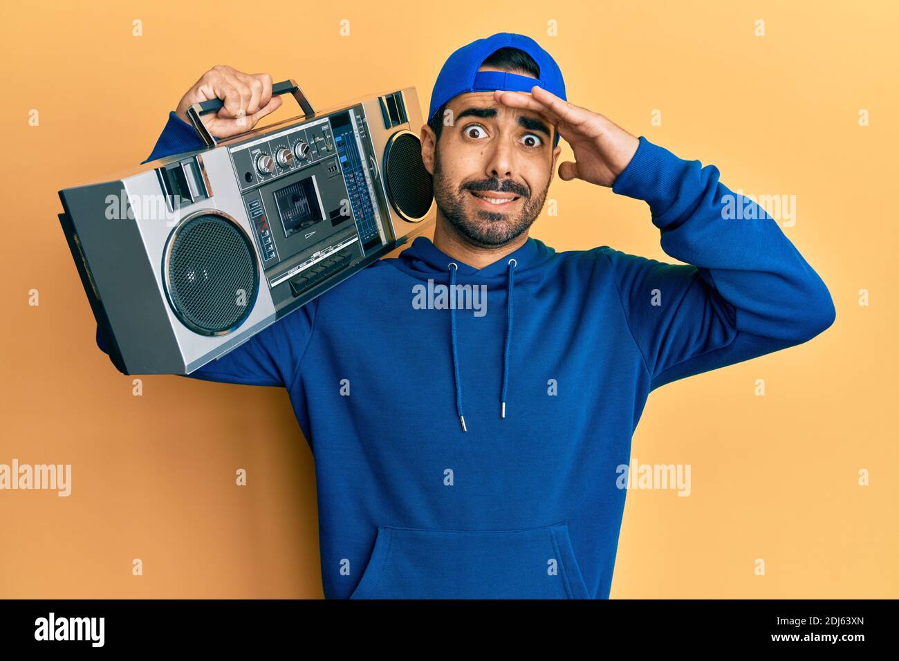 Young hispanic man holding boombox, listening to music stressed and ...