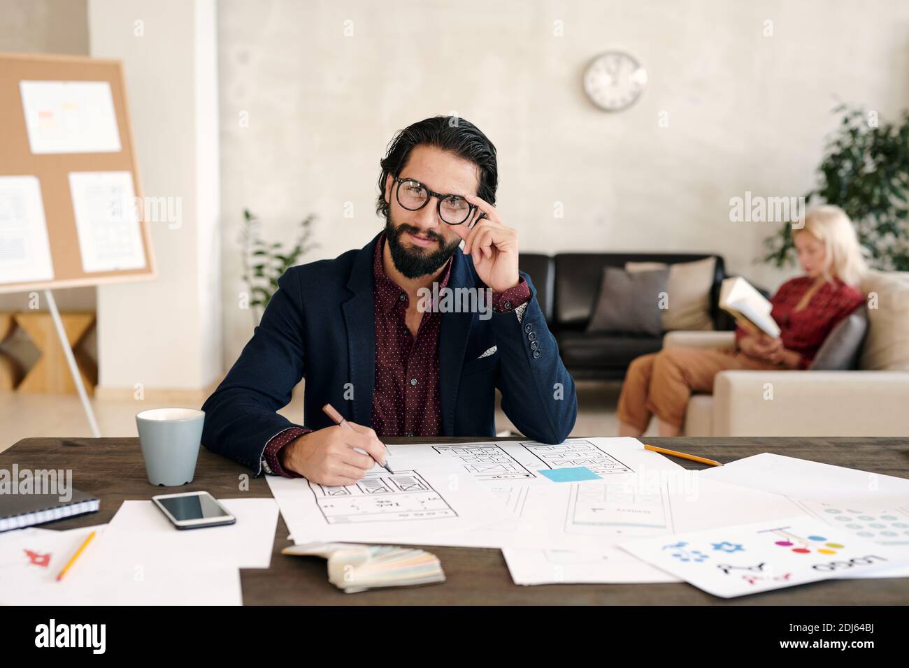 Young bearded successful developer of mobile applications holding ...