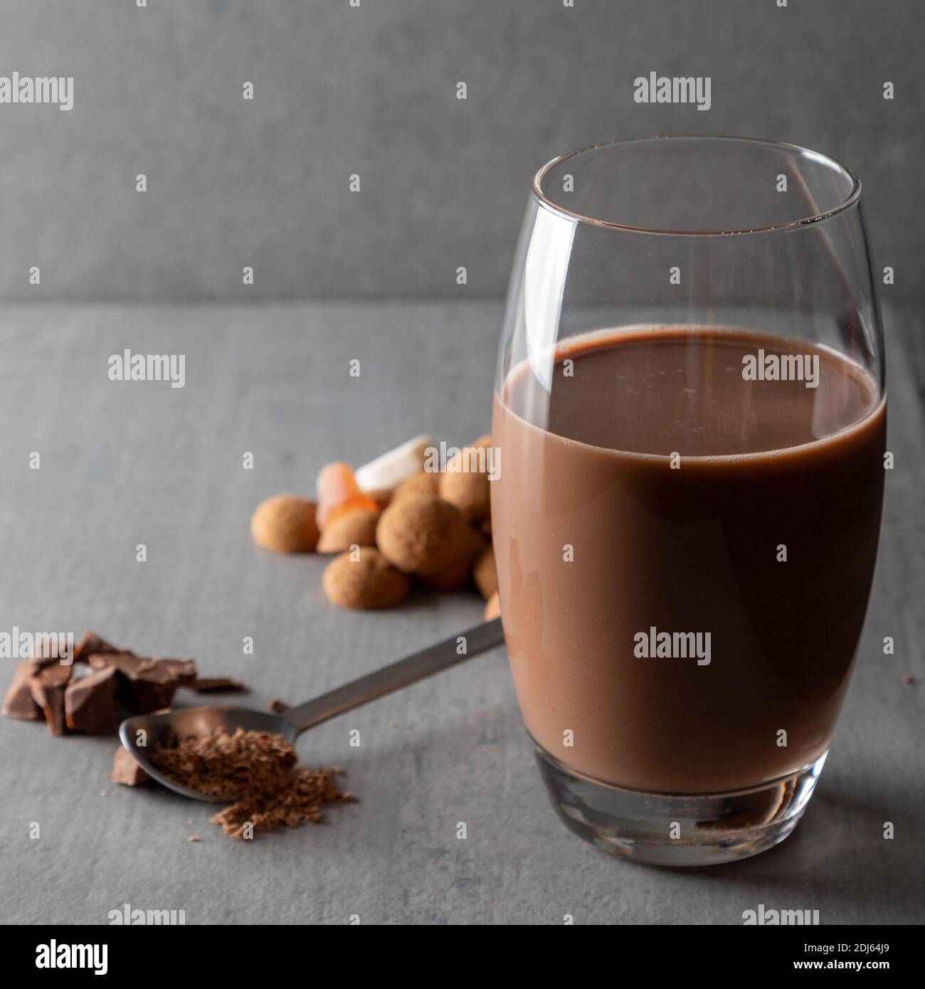 Glass of cold chocolate milk drink presented with an iron spoon and ...
