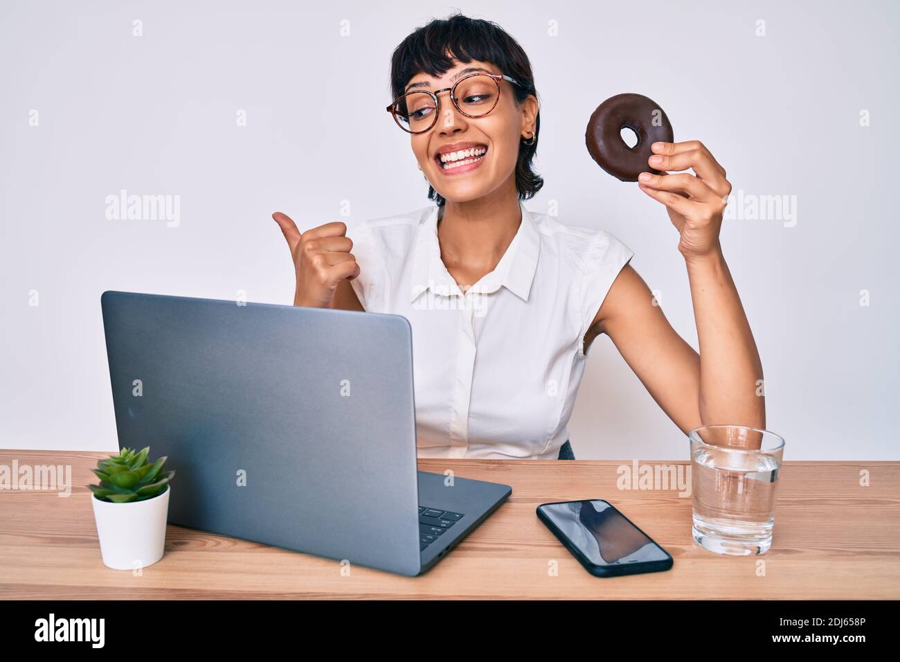 Beautiful brunettte woman working at the office eating chocolate ...