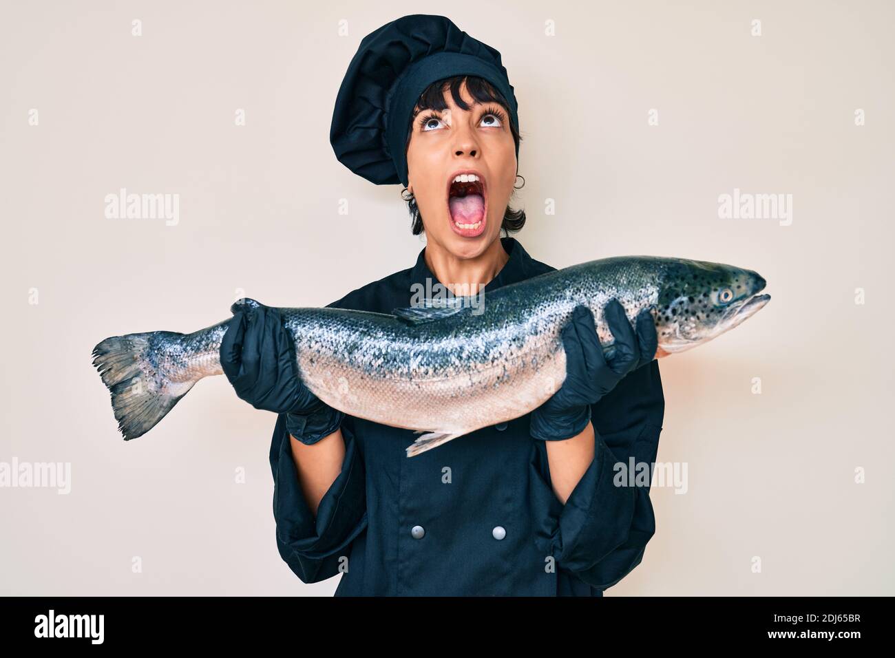 Beautiful brunettte woman professional chef holding fresh salmon fish ...