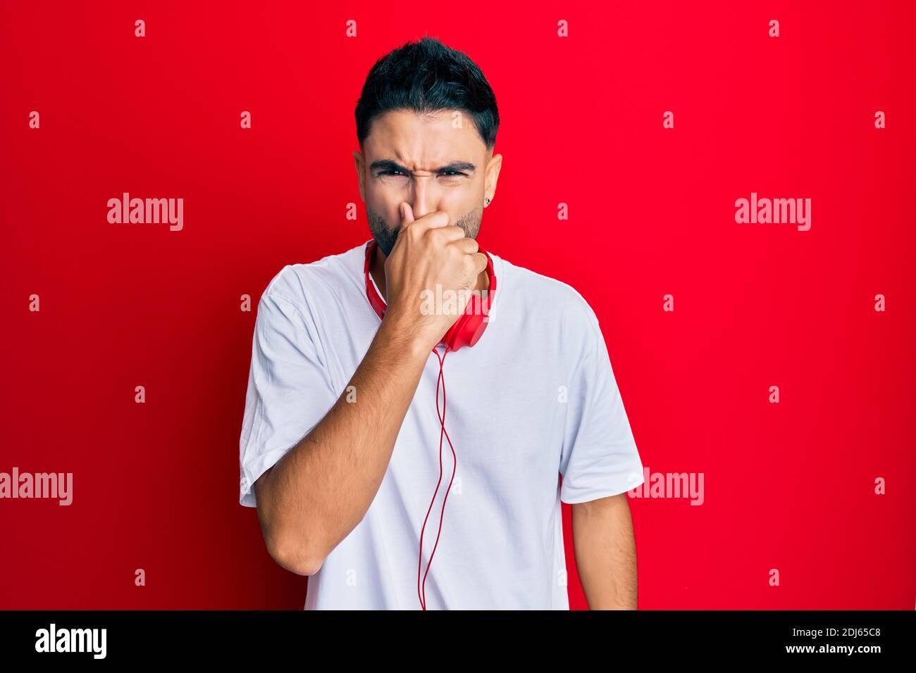 Young man with beard listening to music using headphones smelling ...
