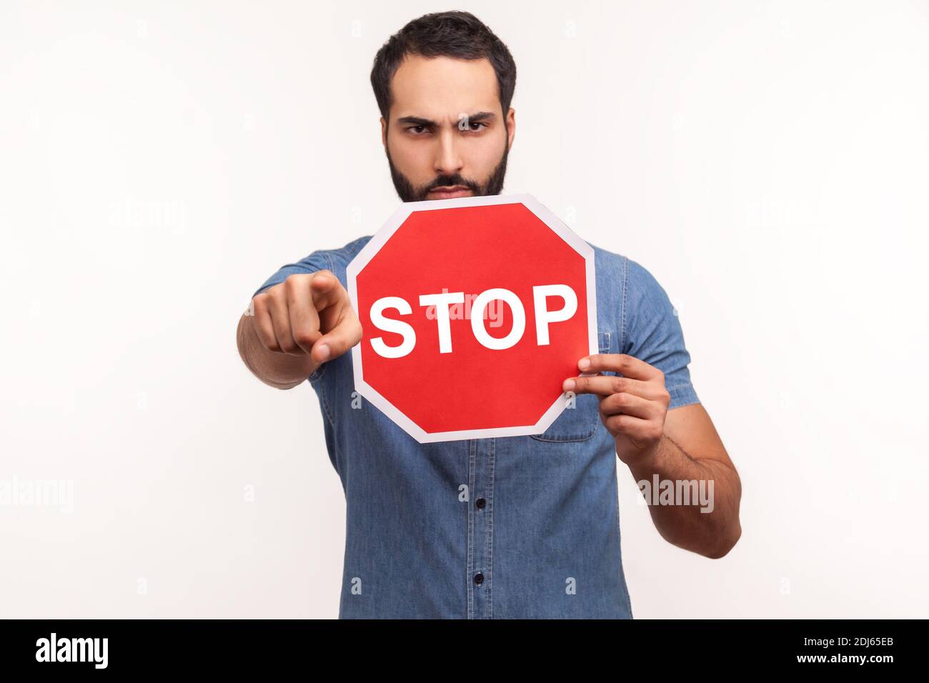 Strict angry man with beard holding stop sign and pointing at camera ...