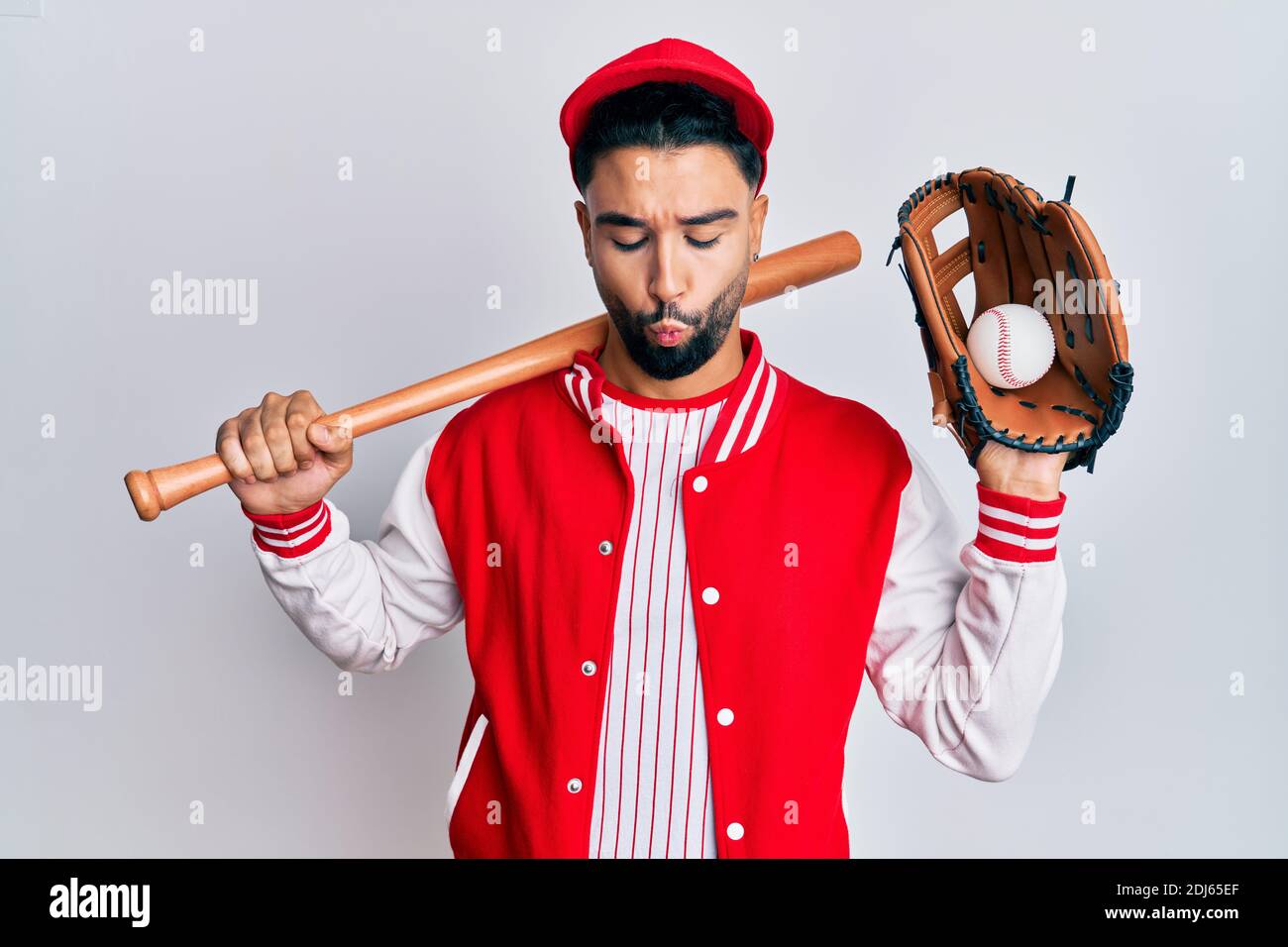 Young man with beard playing baseball holding bat and ball making fish ...