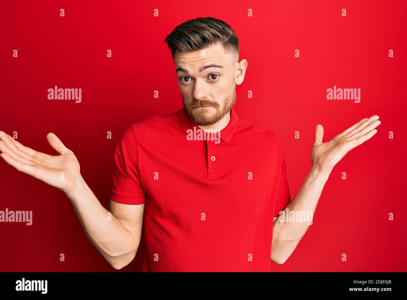 Young redhead man wearing casual clothes clueless and confused with ...