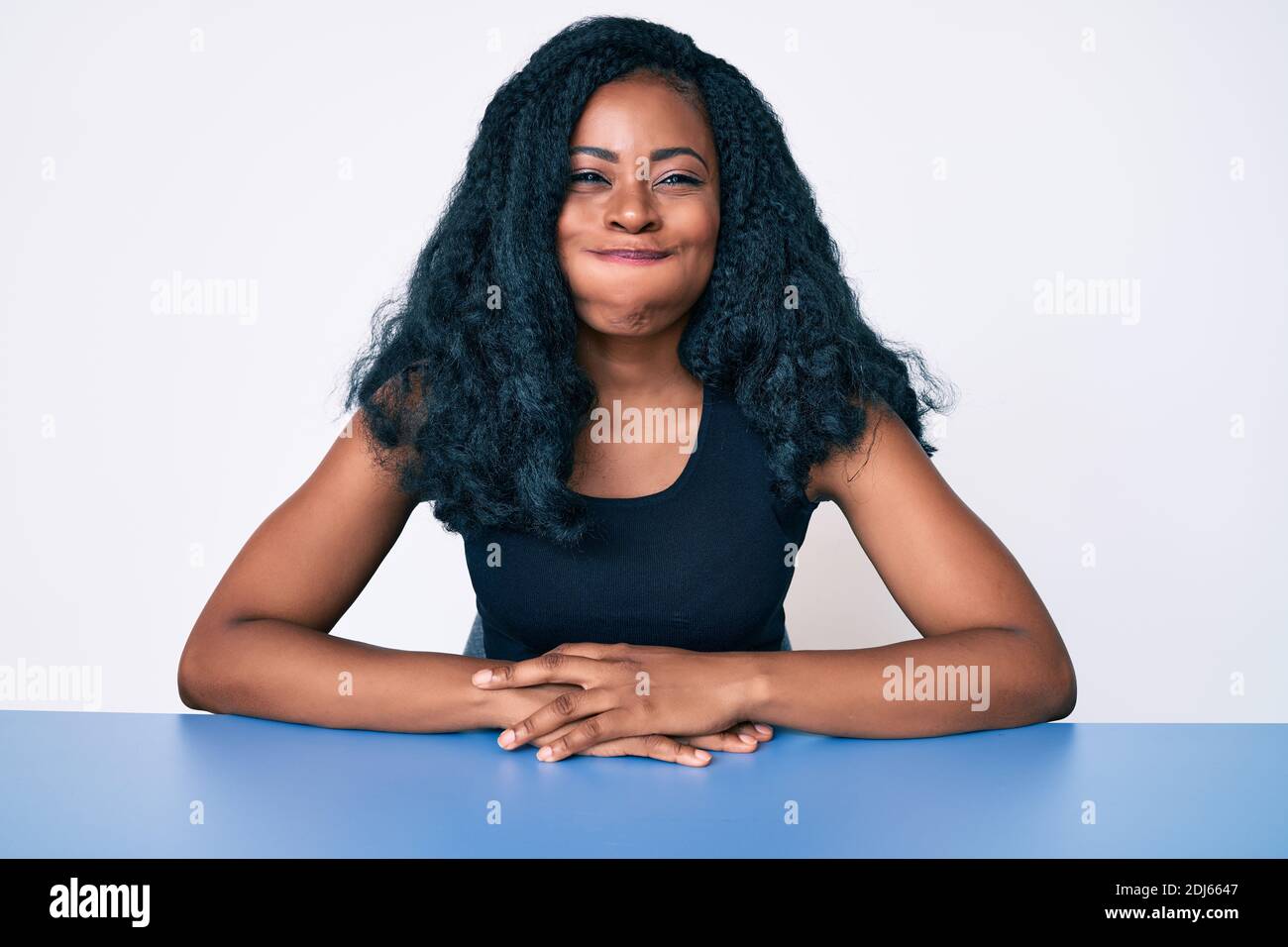 Beautiful african woman wearing casual clothes sitting on the table ...