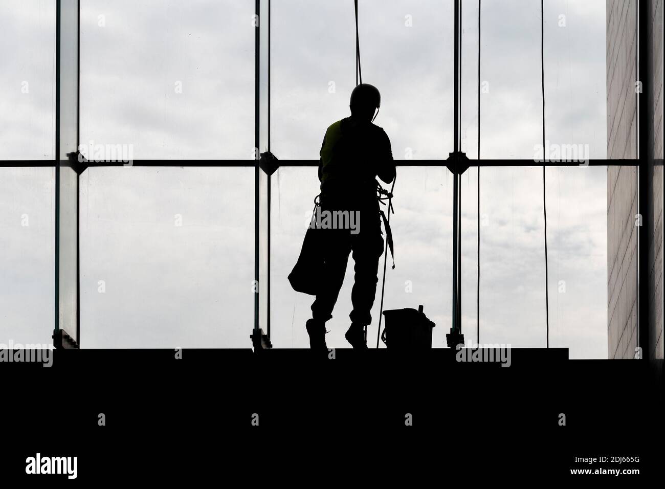 Worker silhouettes cleaning building facade window glass by using ...
