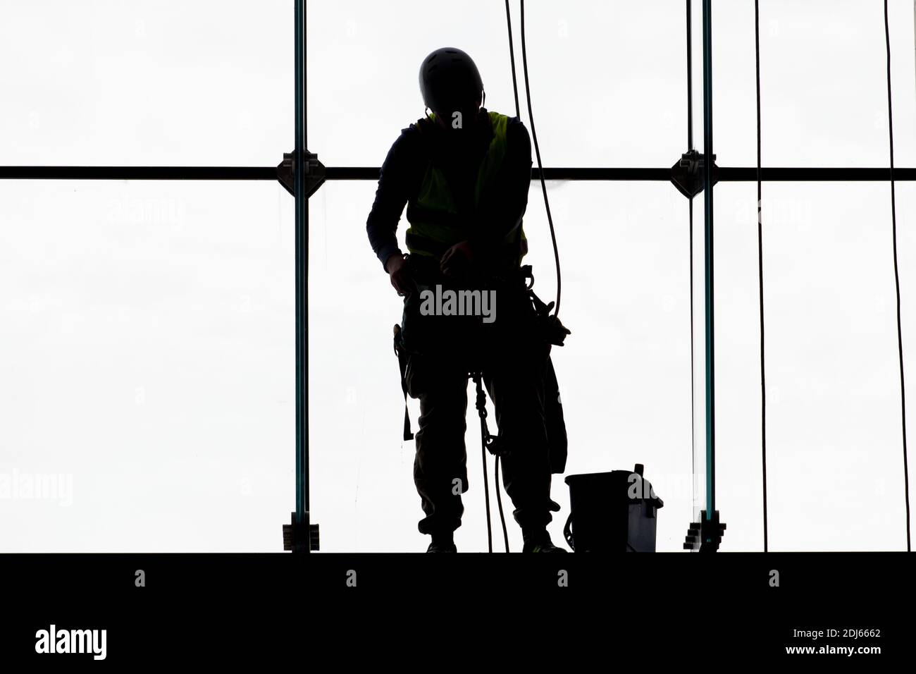 Worker silhouettes washing windows at heights, work with high risk ...