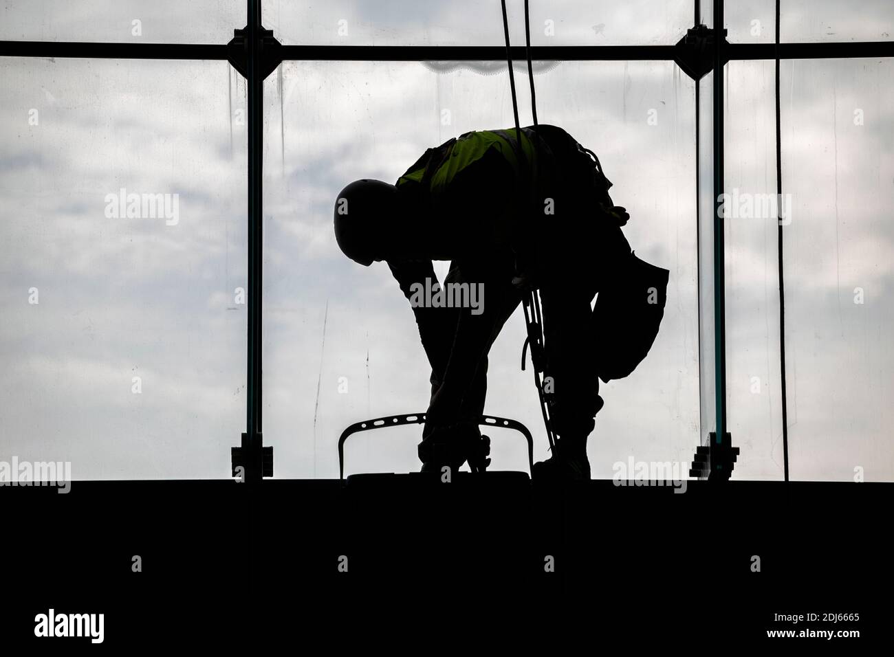 Worker silhouettes cleaning windows on height, cleaning building window ...