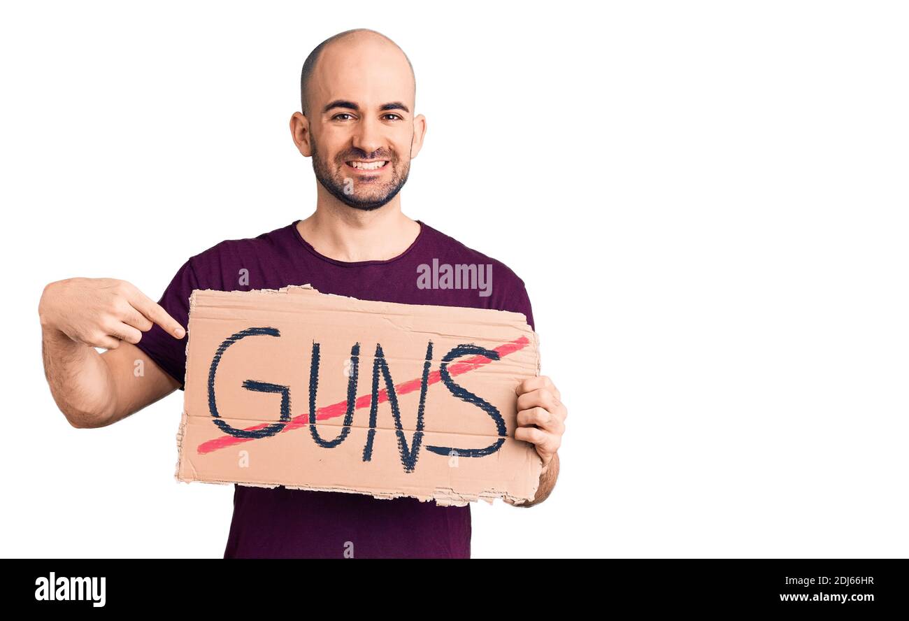 Young handsome man holding prohibited guns banner smiling happy ...