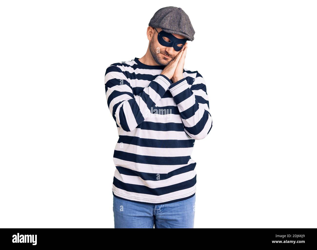 Young handsome man wearing burglar mask sleeping tired dreaming and ...