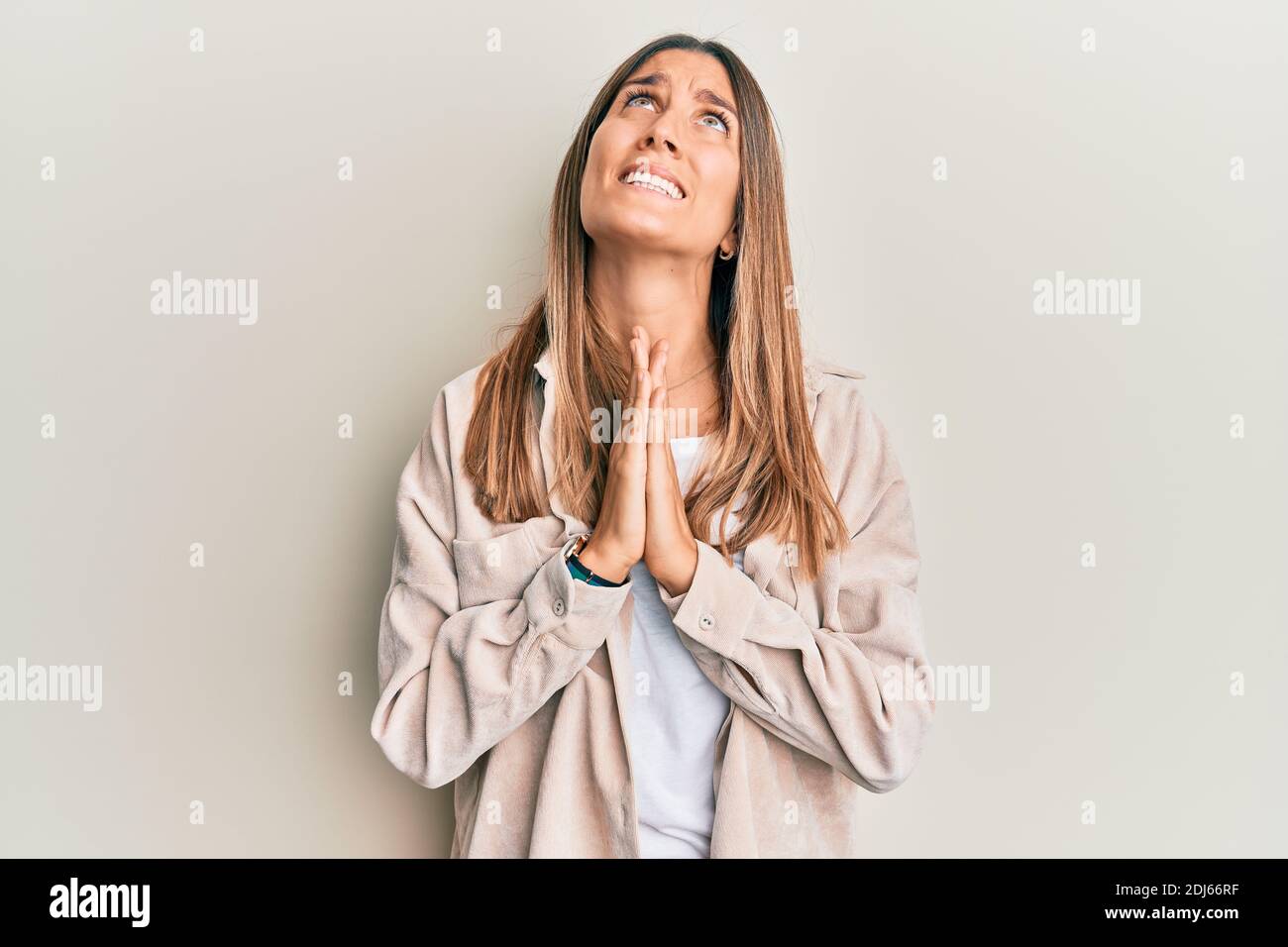 Brunette young woman wearing casual clothes begging and praying with ...