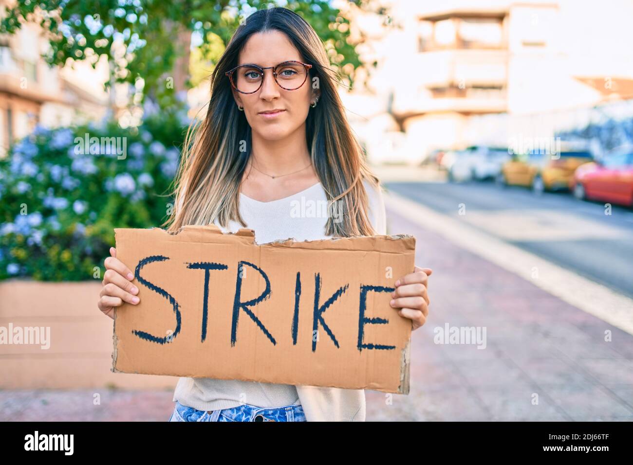 Young caucasian woman with serious expression holding strike banner ...