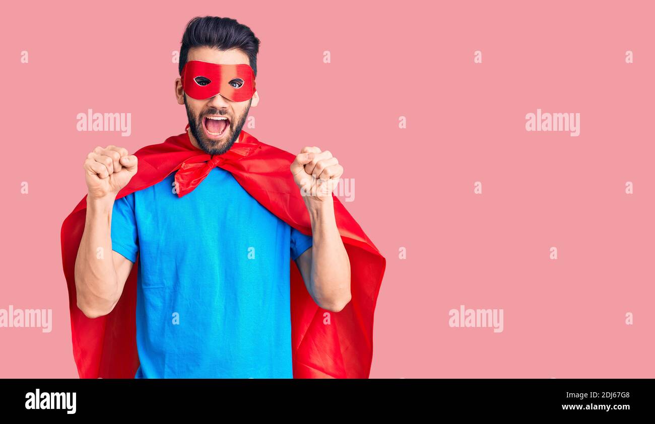 Young handsome man with beard wearing super hero costume celebrating ...