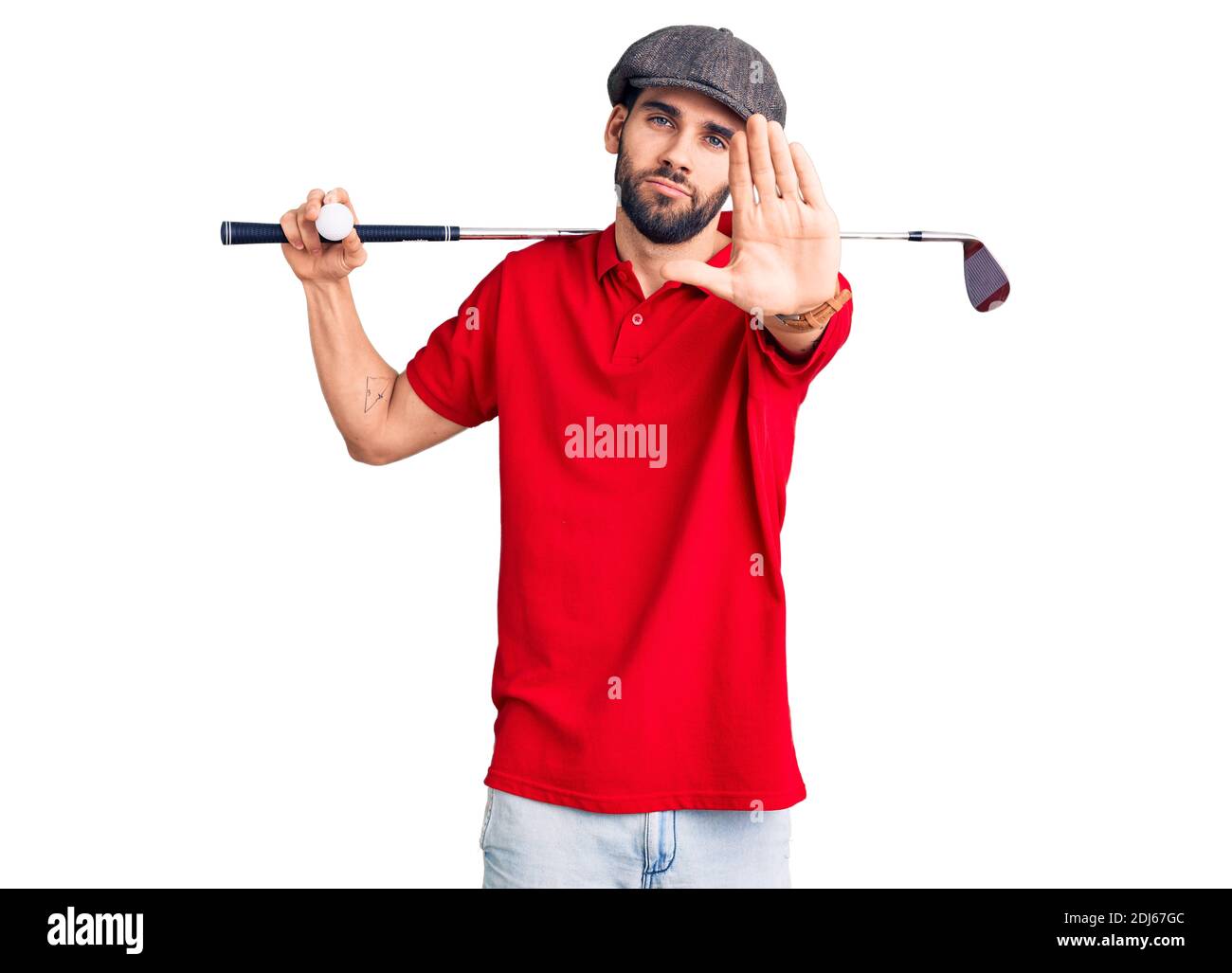 Young handsome man with beard playing golf holding club and ball with ...