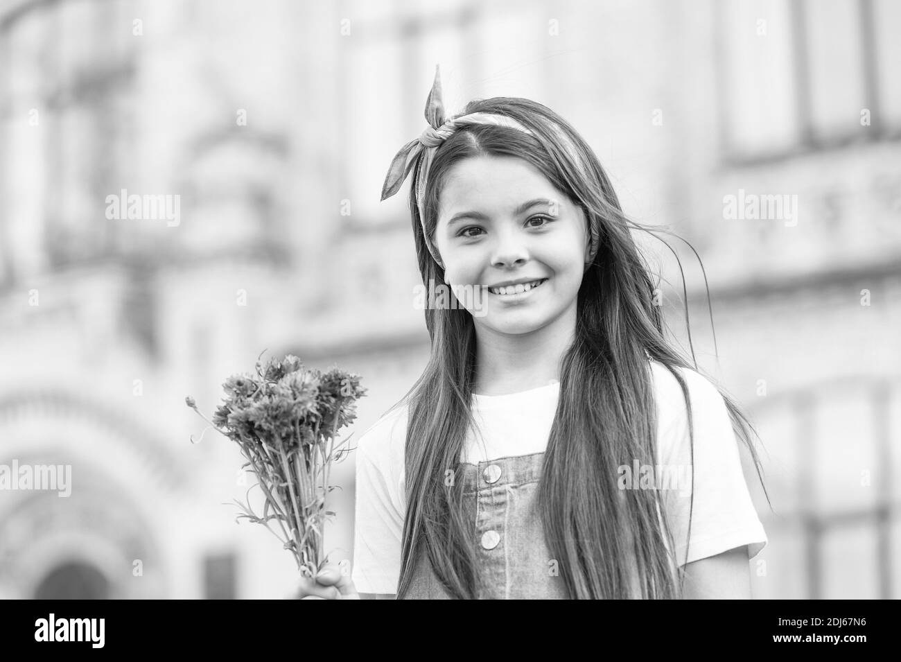 Shes cool, ooh girl. Happy girl hold flowers outdoors. Little girl with ...