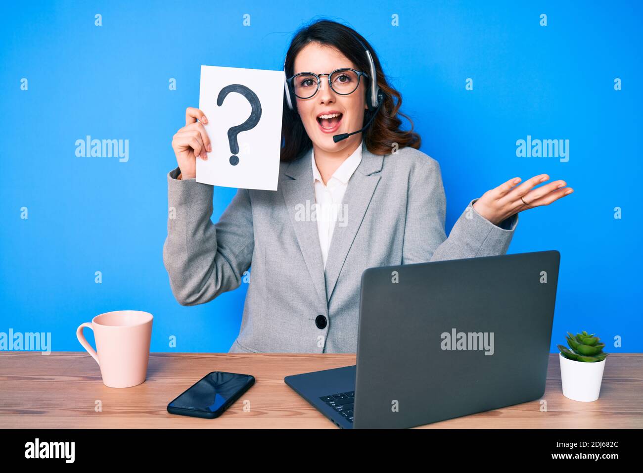 Young beautiful brunette woman wearing operator headset holding ...