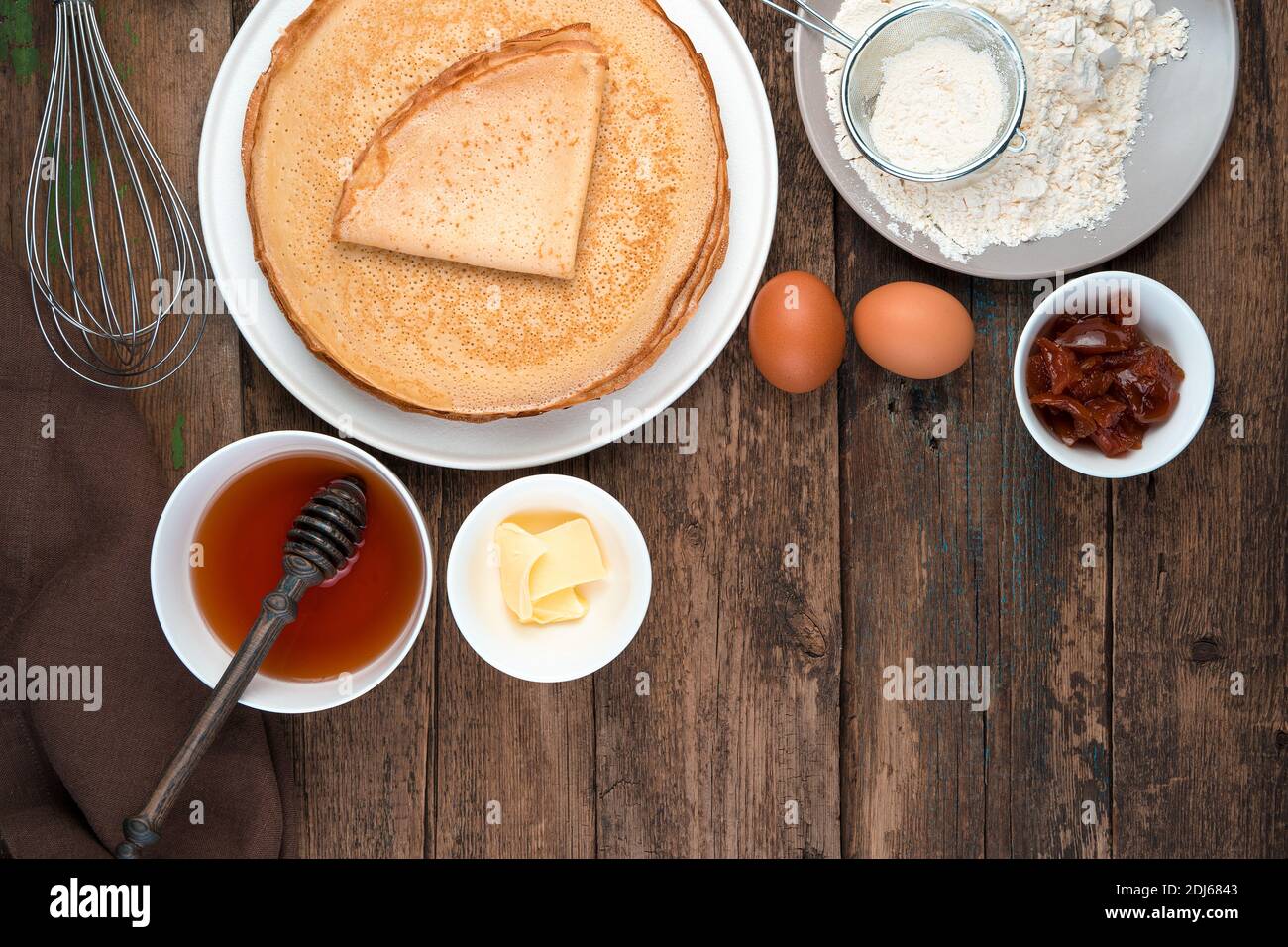 Ingredients for making pancakes, and ready-made pancakes on a brown ...