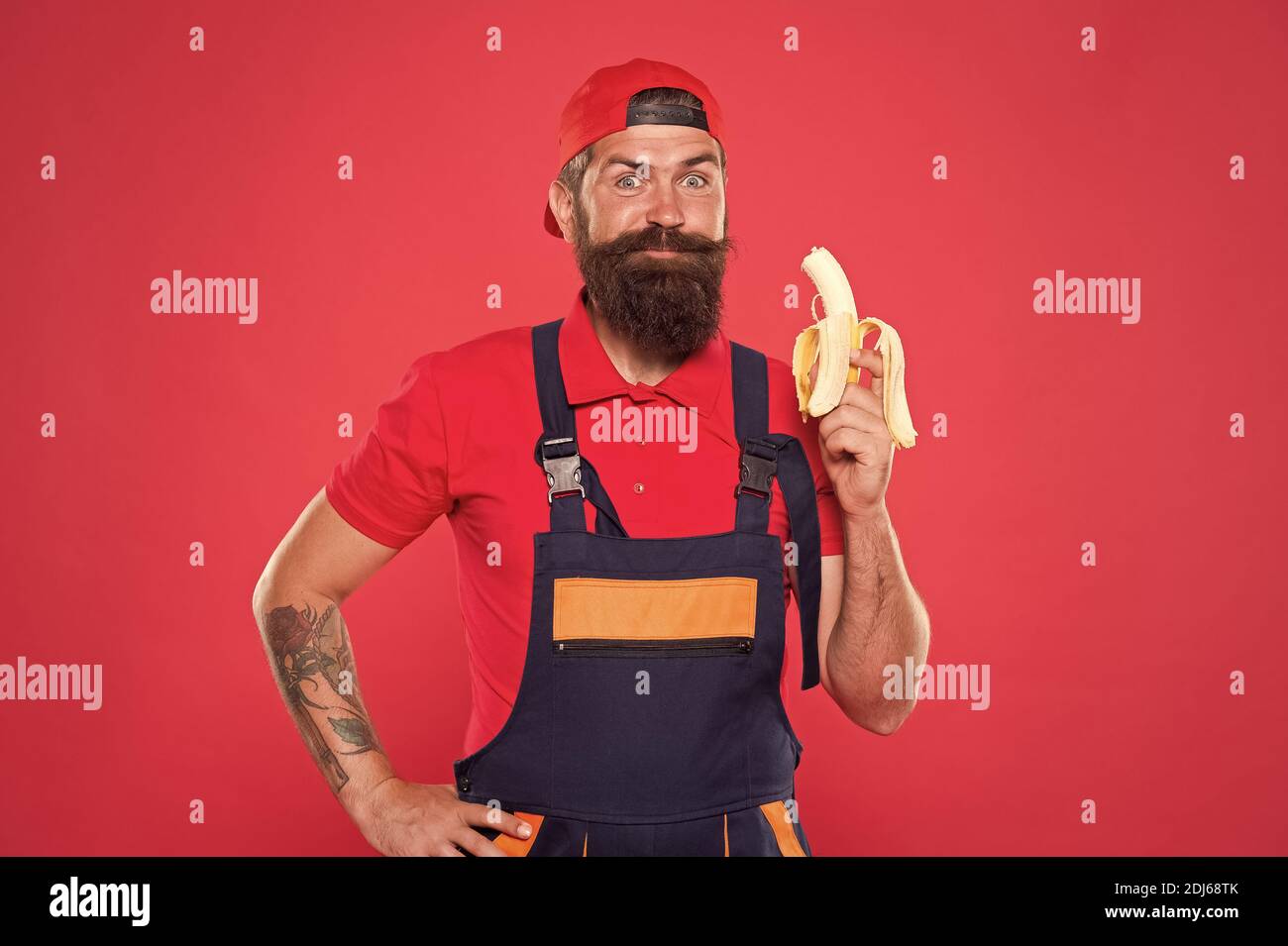 Lunch time. Bearded man in uniform and cap eating banana. Worker ...