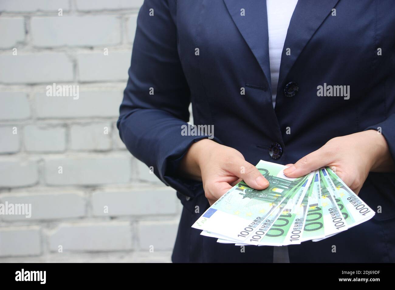 Businesswoman wearing dark blue suit counting money in 100 Euro ...