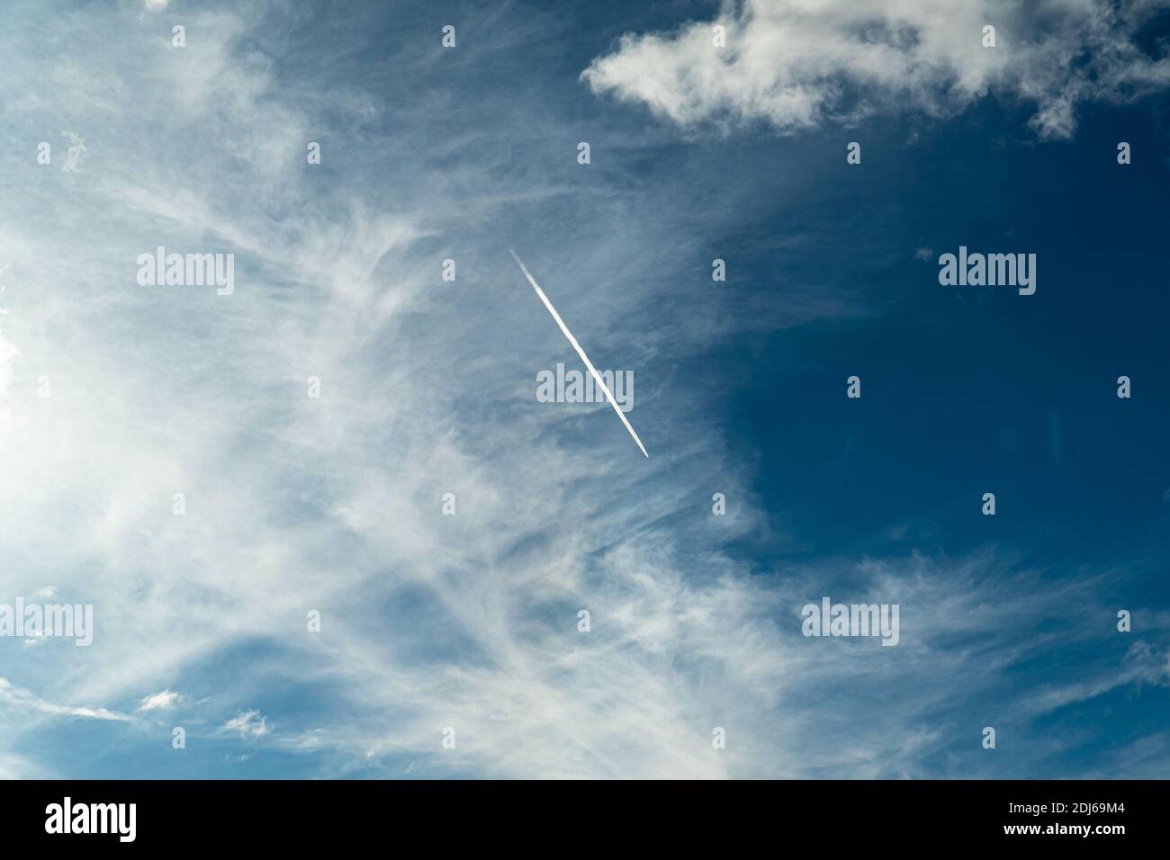 Trace of a passing plane on a beautiful blue sky with white clouds ...