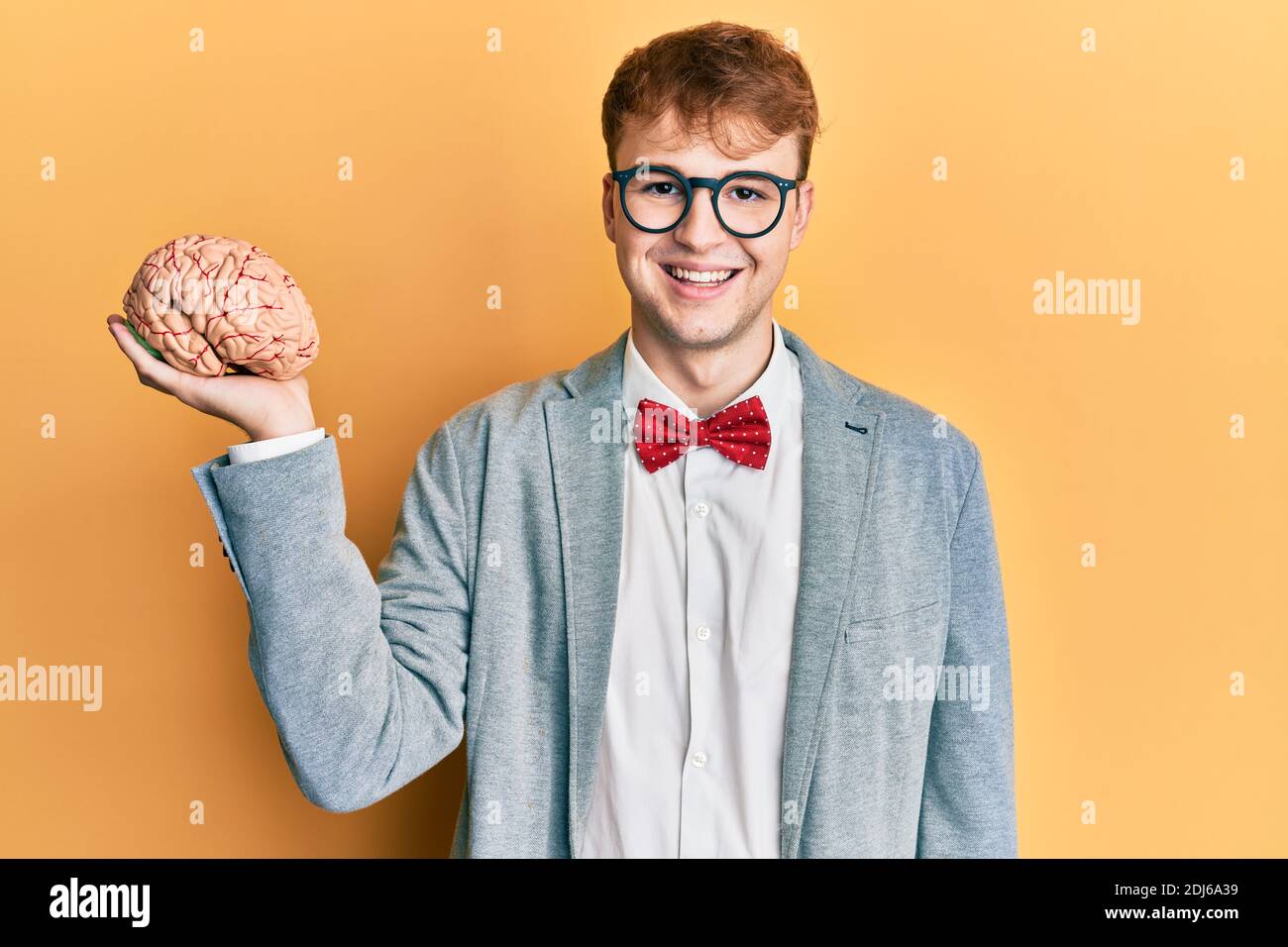 Young caucasian man wearing glasses holding brain looking positive and ...