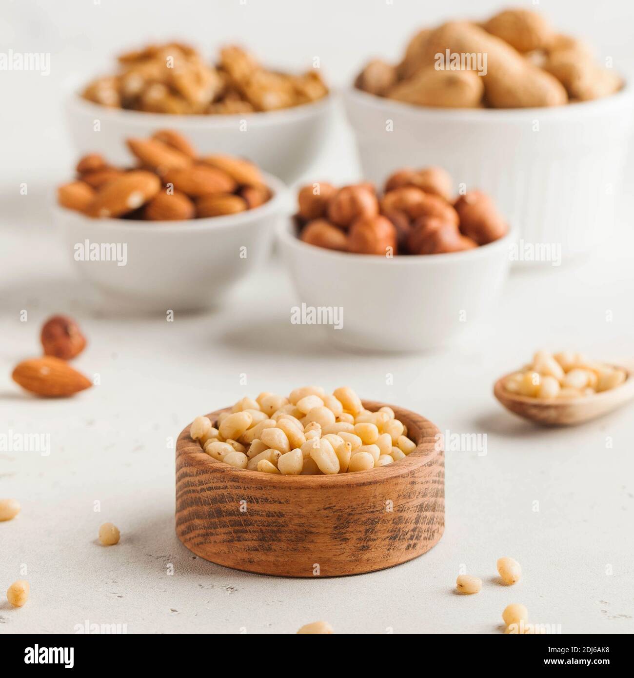 A handful of pine nuts in a wooden bowl, assorted nuts on a light ...