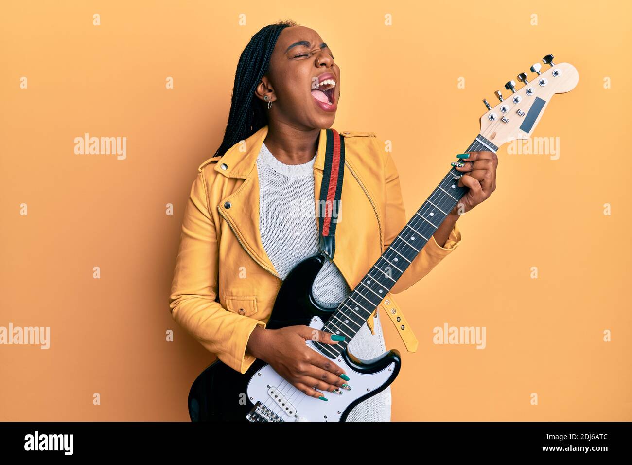 Young african american woman playing electric guitar angry and mad ...