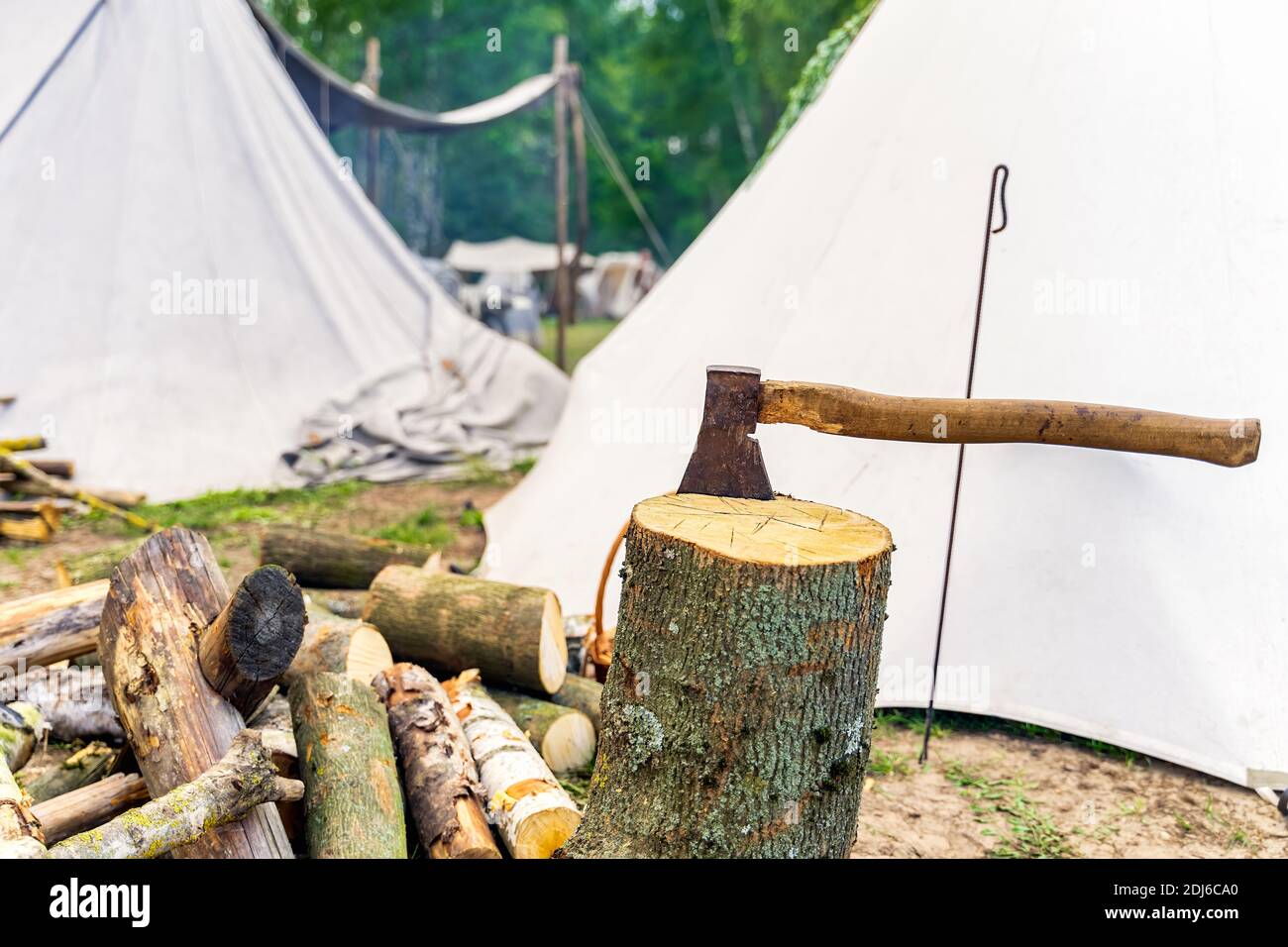 An axe stuck in the stump of a tree with chopped logs at historical ...