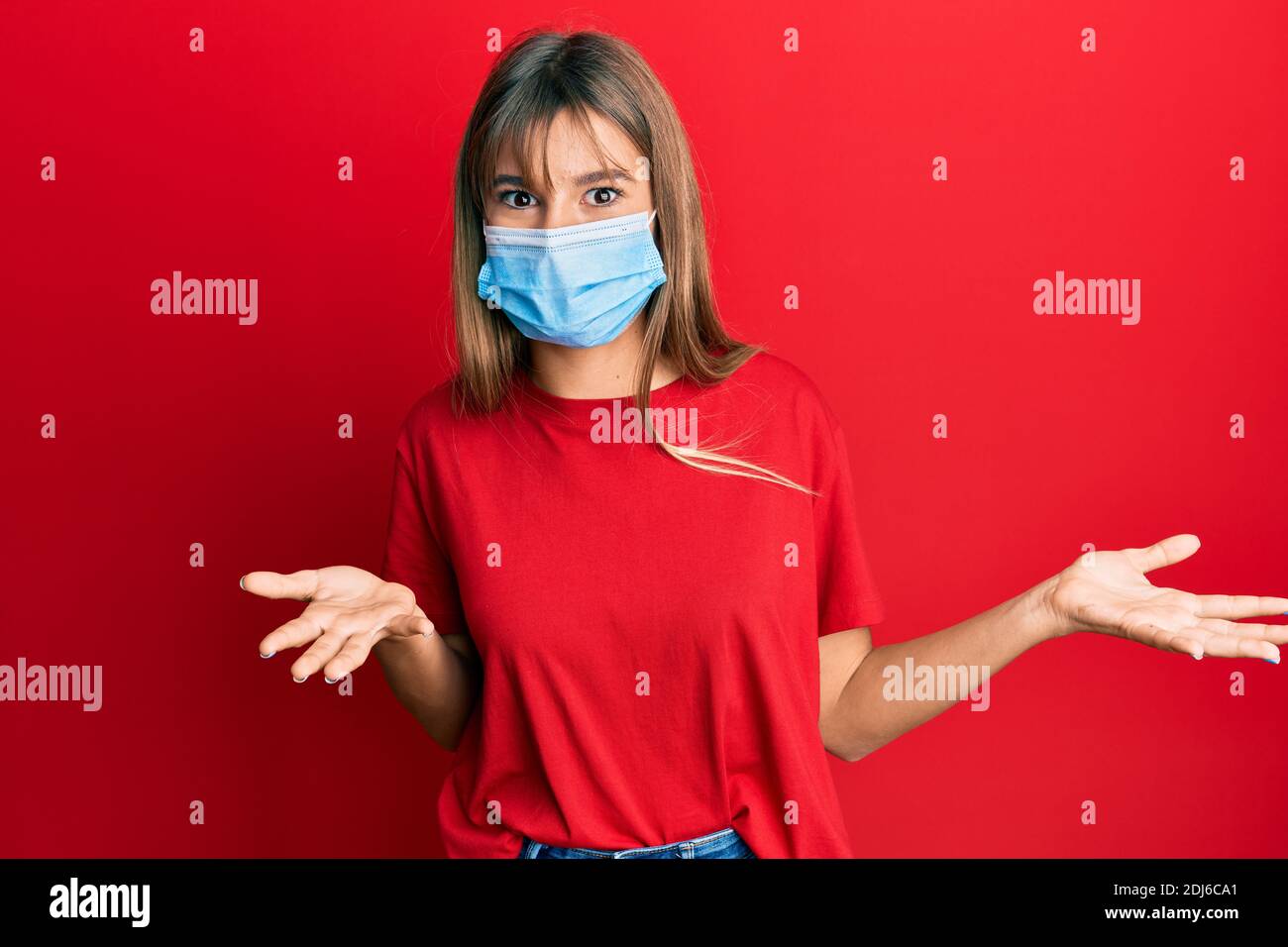 Teenager caucasian girl wearing medical mask clueless and confused ...
