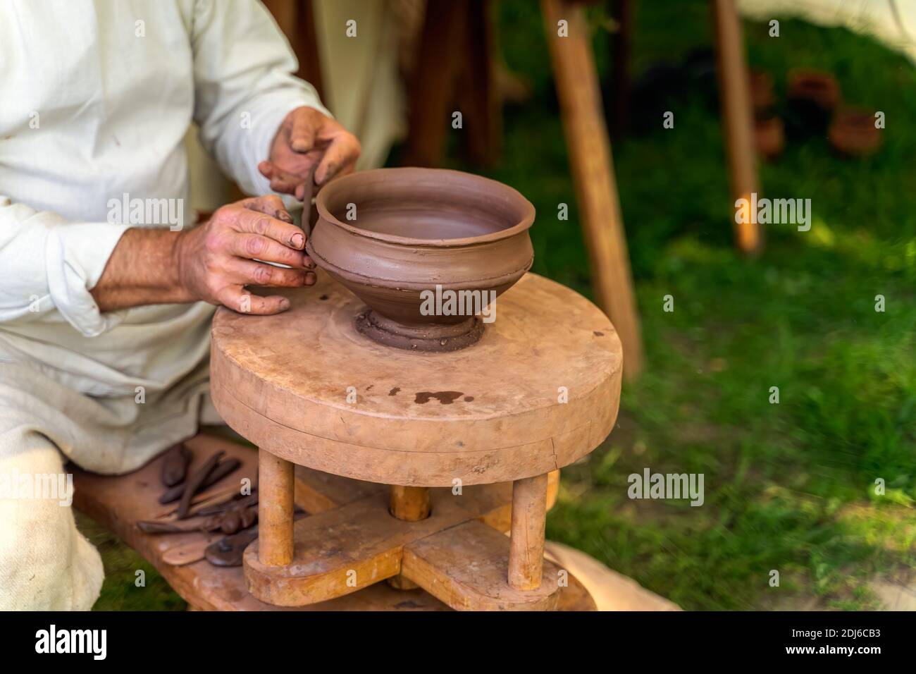 Craftsman hand making pottery from clay on potters wheel at historical ...