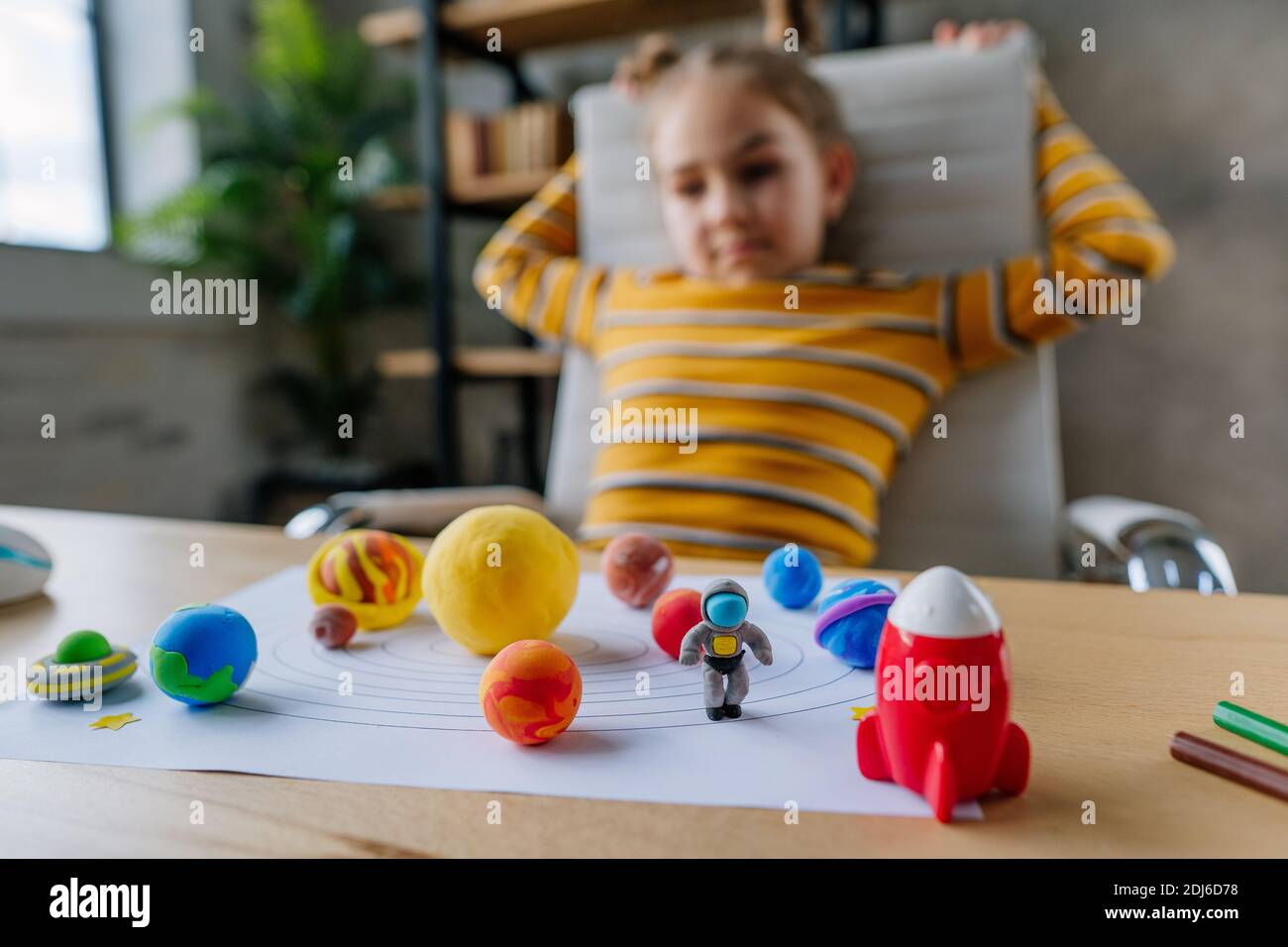 8 years old girl study Solar system sitting on the desk in the room ...