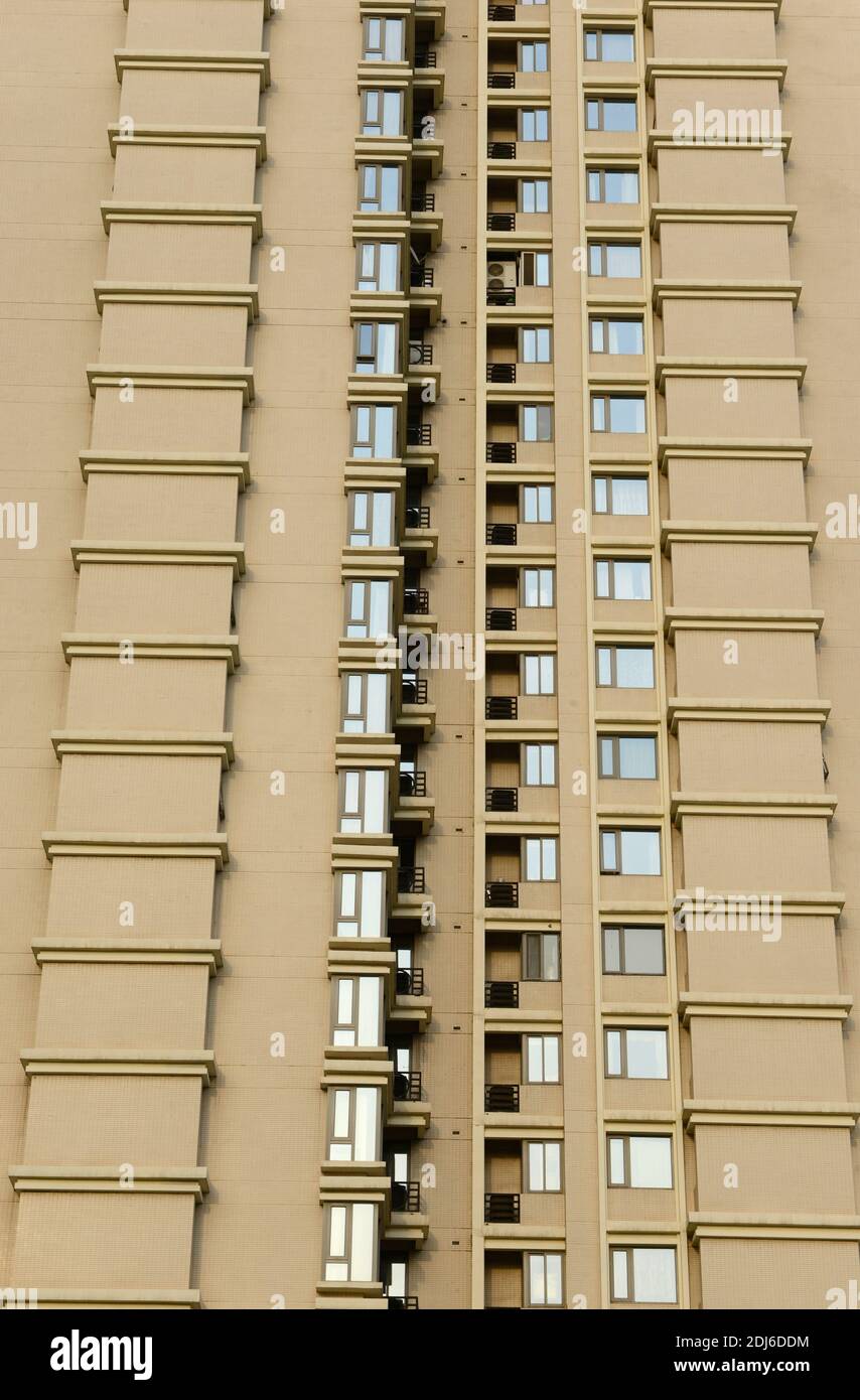 A sandy coloured apartment building with many clear stories of windows ...