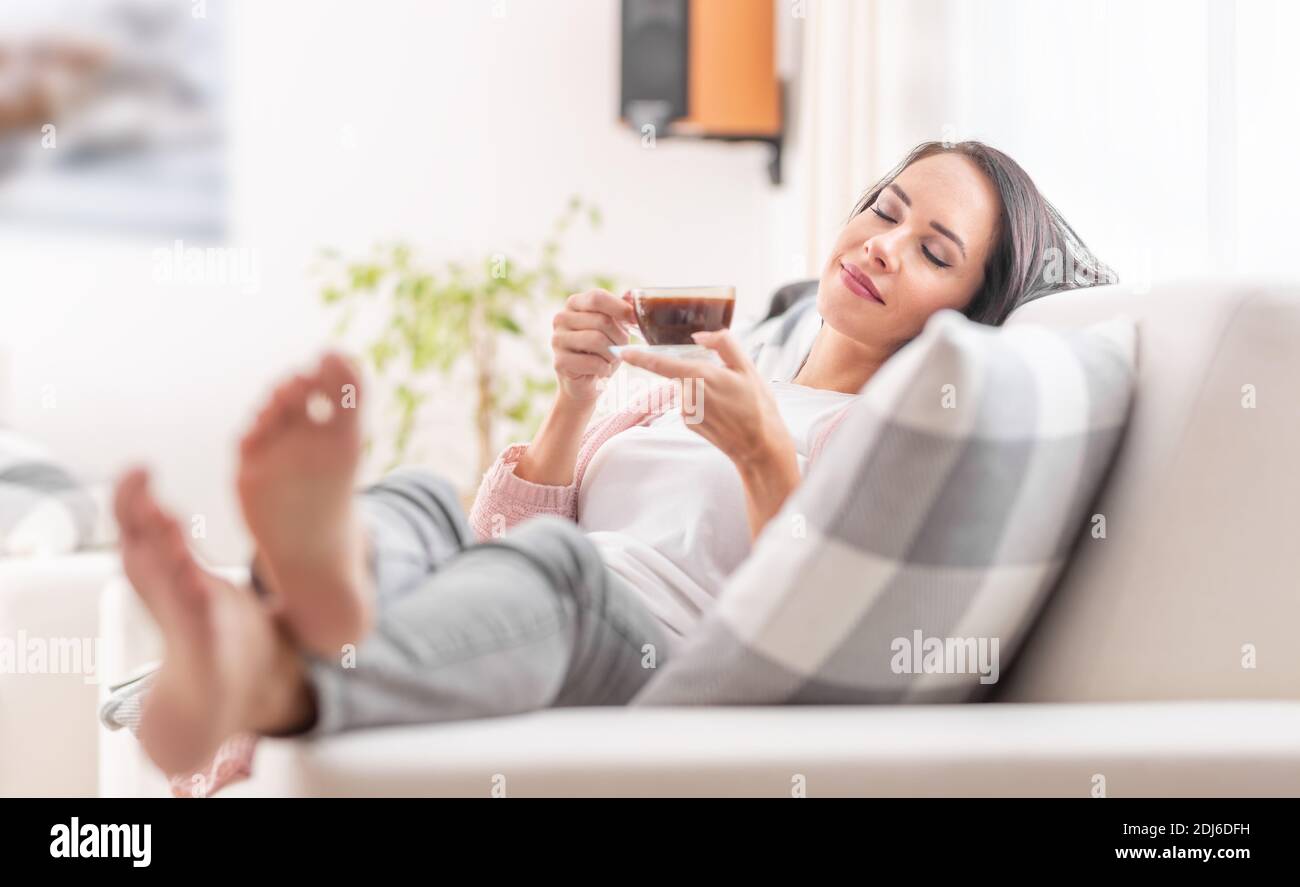 A woman with feet up in comfy outfit enjoys a peaceful time of ...
