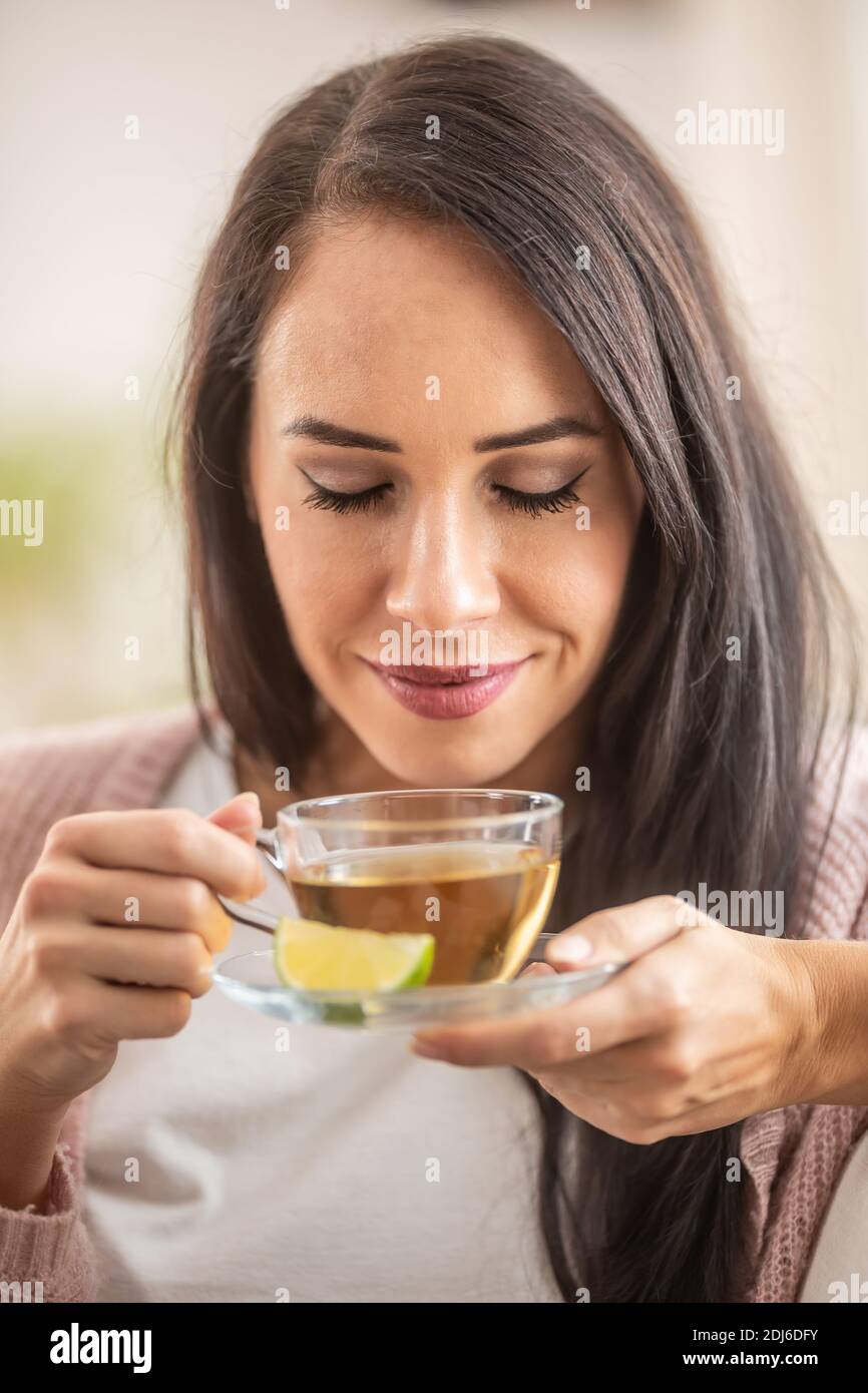 Good looking female enjoys the smell of a freshly brewed tea with eyes ...
