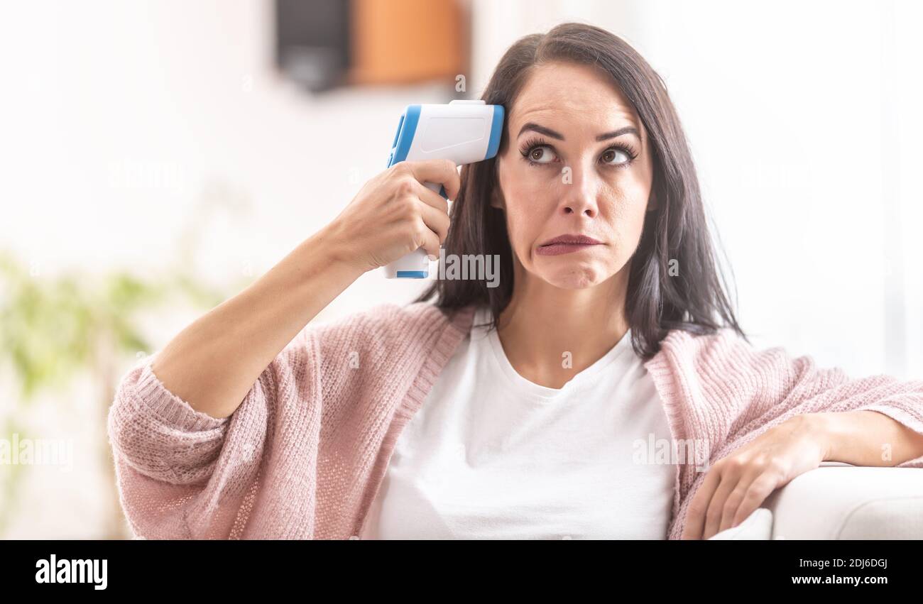Woman not knowing how to use an infrared forehead thermometer Stock ...