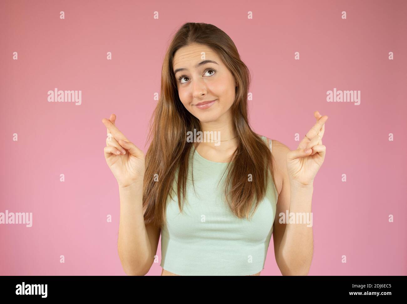 Portrait of pretty woman fingers crossed isolated on pink background ...