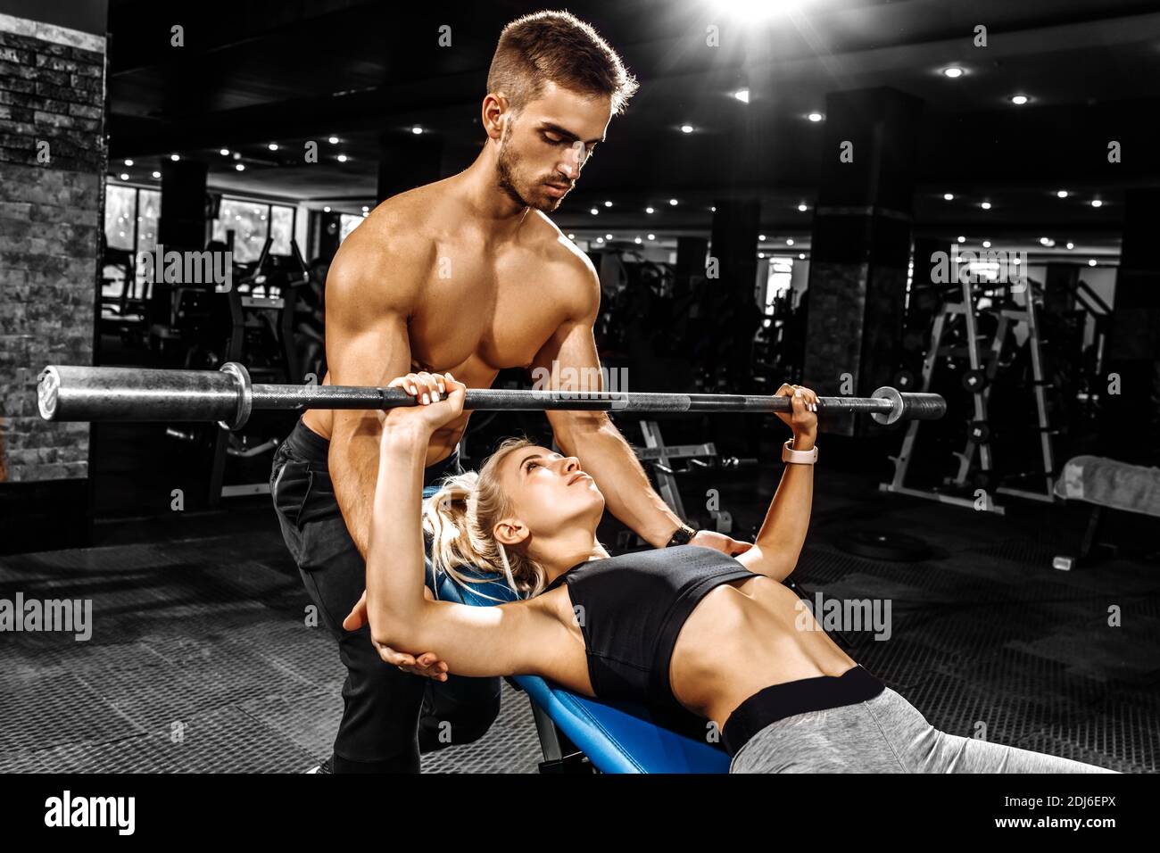 Personal Trainer Man Helping Woman To Work Out With Heavy Dumbbells In