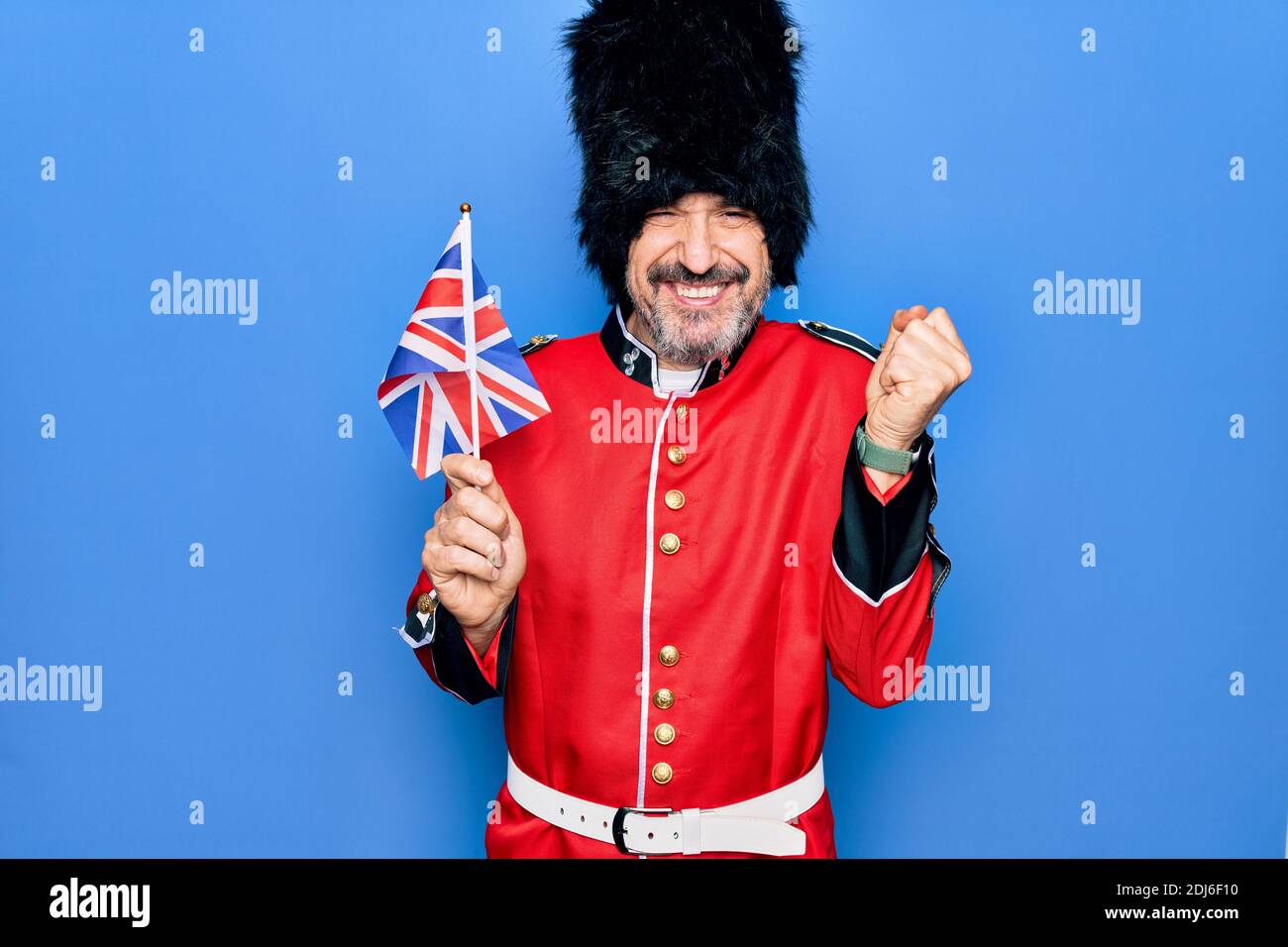 Middle age handsome wales guard man wearing traditional uniform holding ...