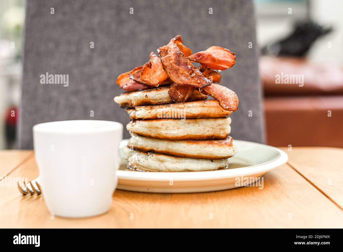 Pancake stack with golden syrup and a large portion of bacon as a ...