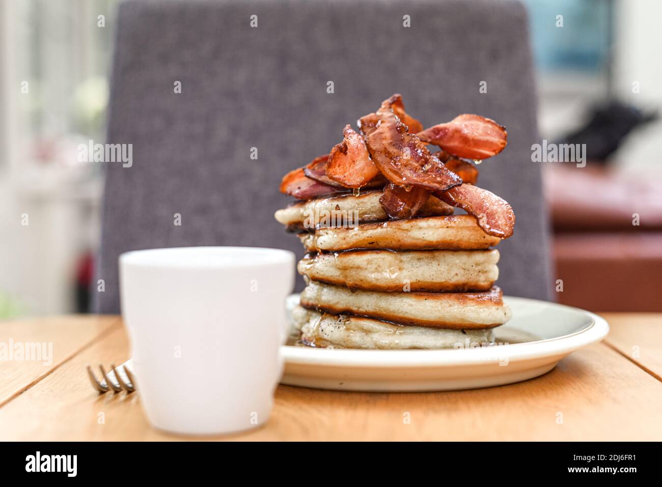 Pancake stack with golden syrup and a large portion of bacon as a ...
