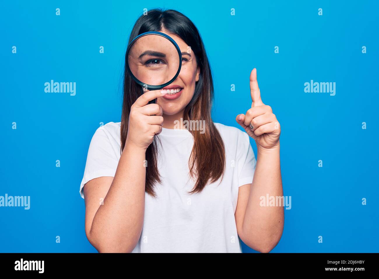 Young beautiful brunette woman using magnifying glass over isolated ...