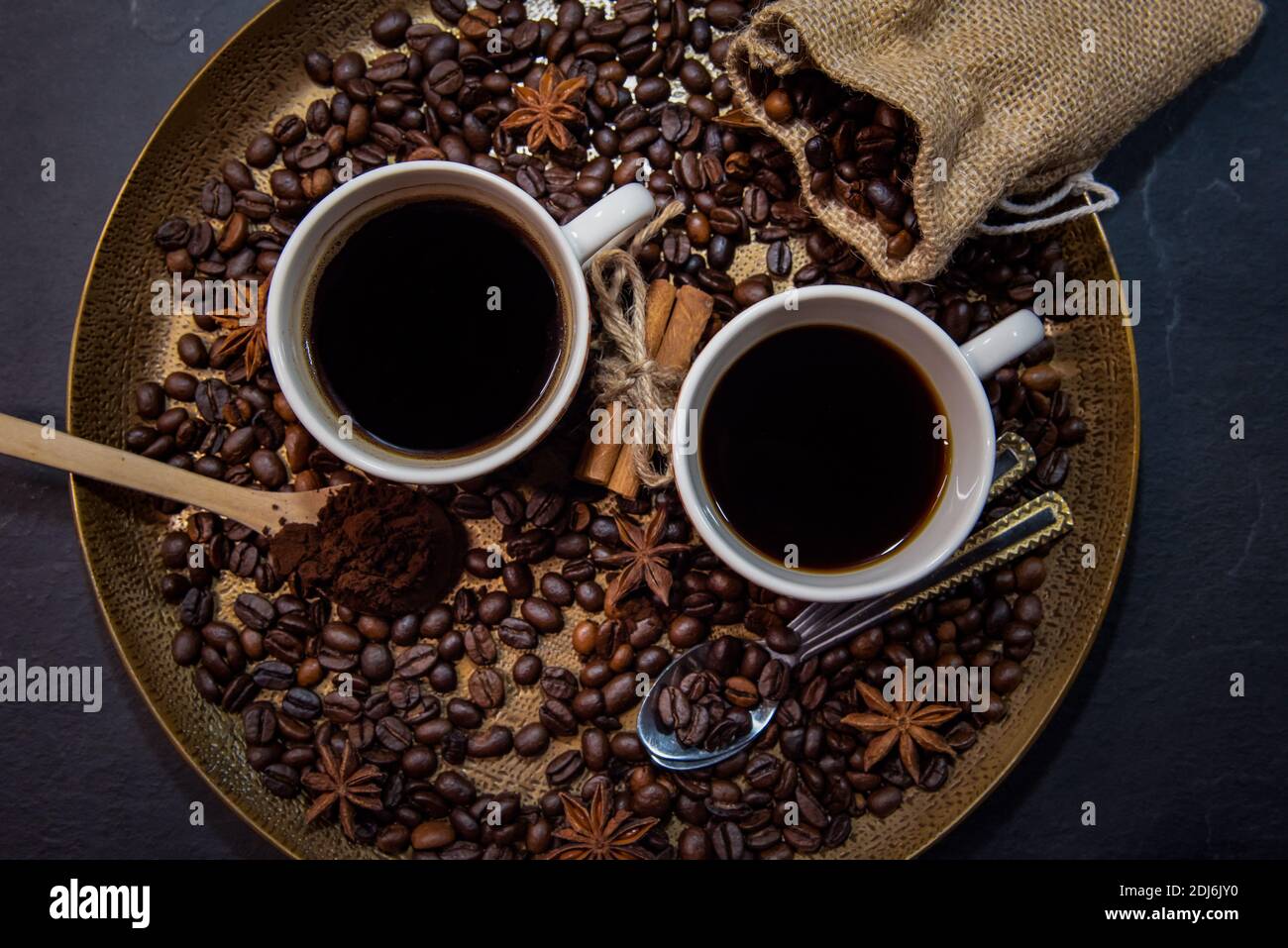 Top down view of two cups of coffee on a golden serving tray surrounded ...