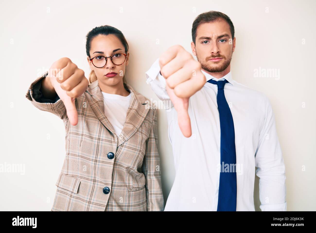 Beautiful couple wearing business clothes looking unhappy and angry ...