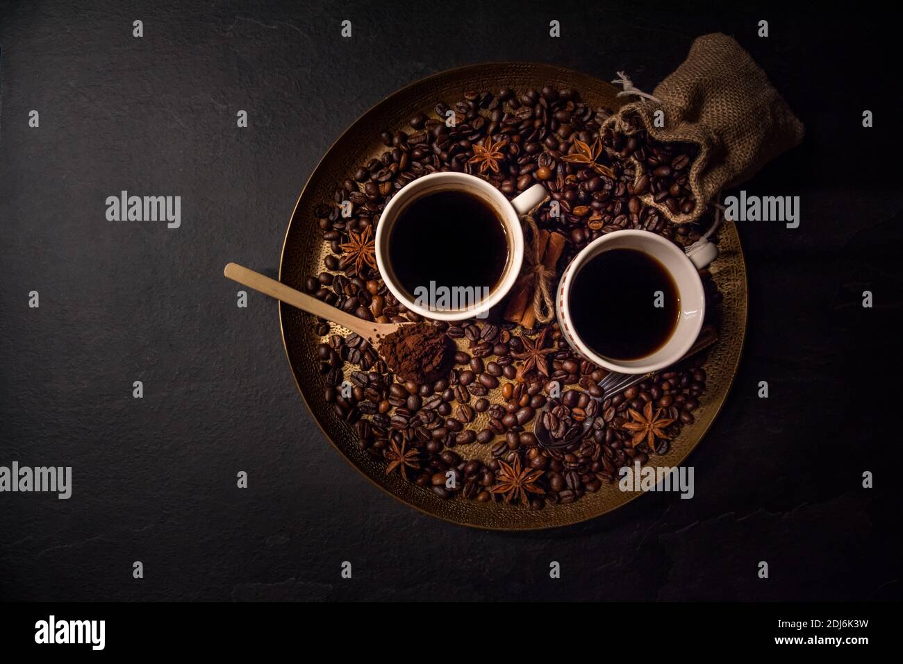 Top down view of two cups of coffee on a golden serving tray surrounded ...