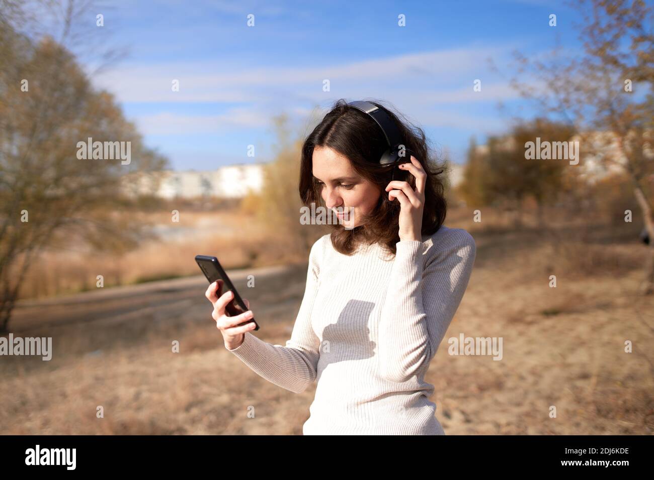 Woman smiling while listening to the music from her smart headphones ...