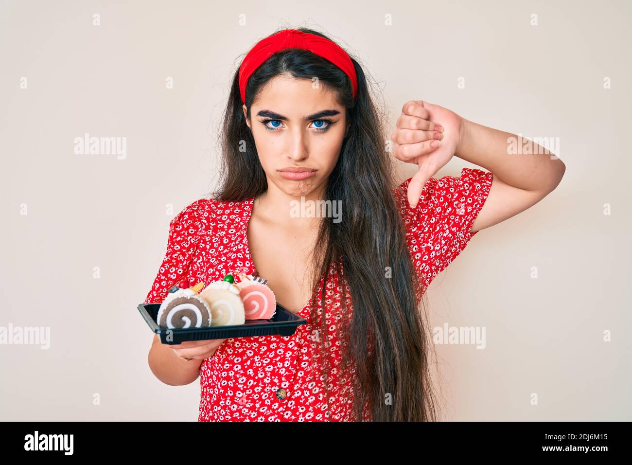 Brunette teenager girl holding cake sweets with angry face, negative ...